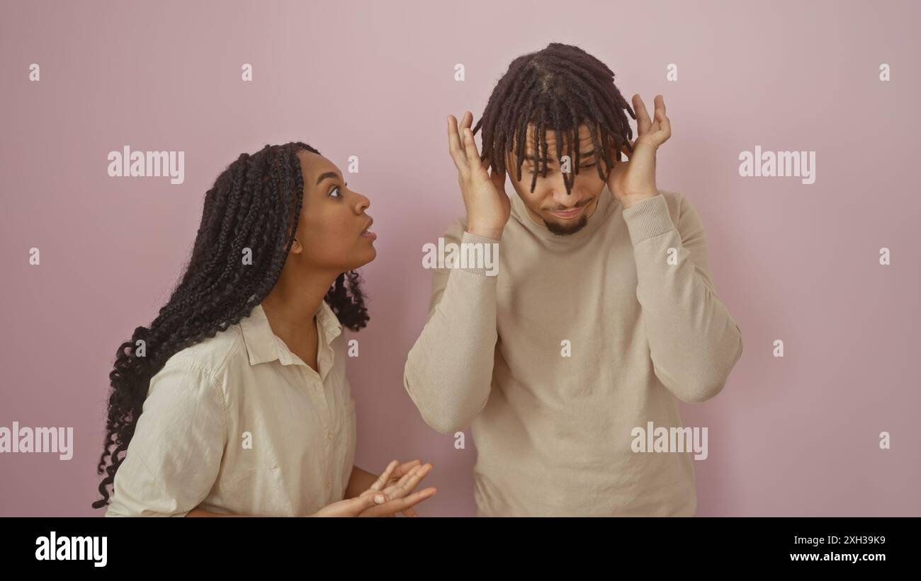 A woman confronts a man covering his ears against a pink background ...