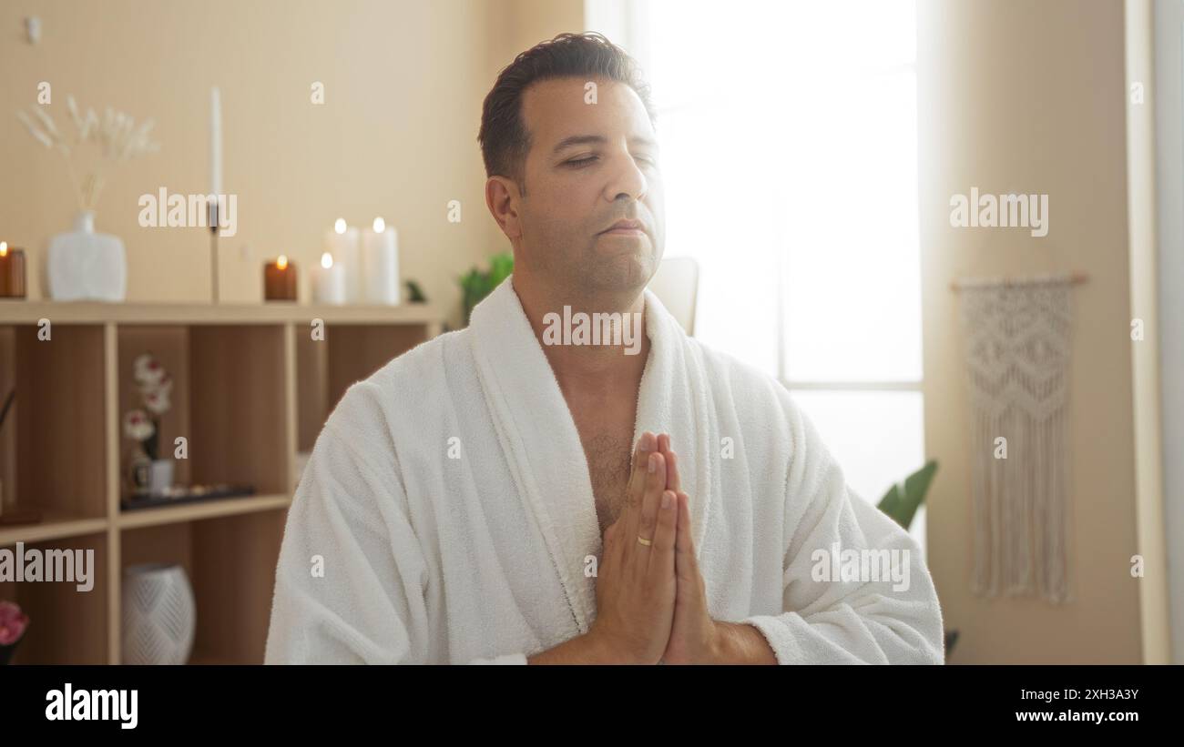 Hispanic man meditating in spa wellness center wearing white robe with ...