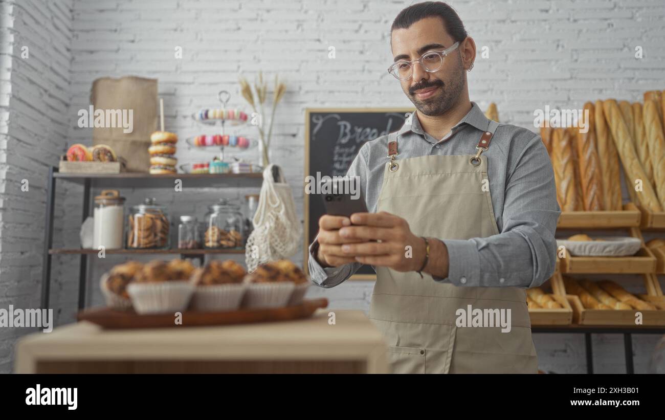 Young man in a bakery shop using his smartphone with a display of ...