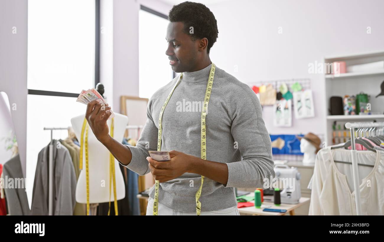 African man counting money in a tailor shop with measuring tape around ...