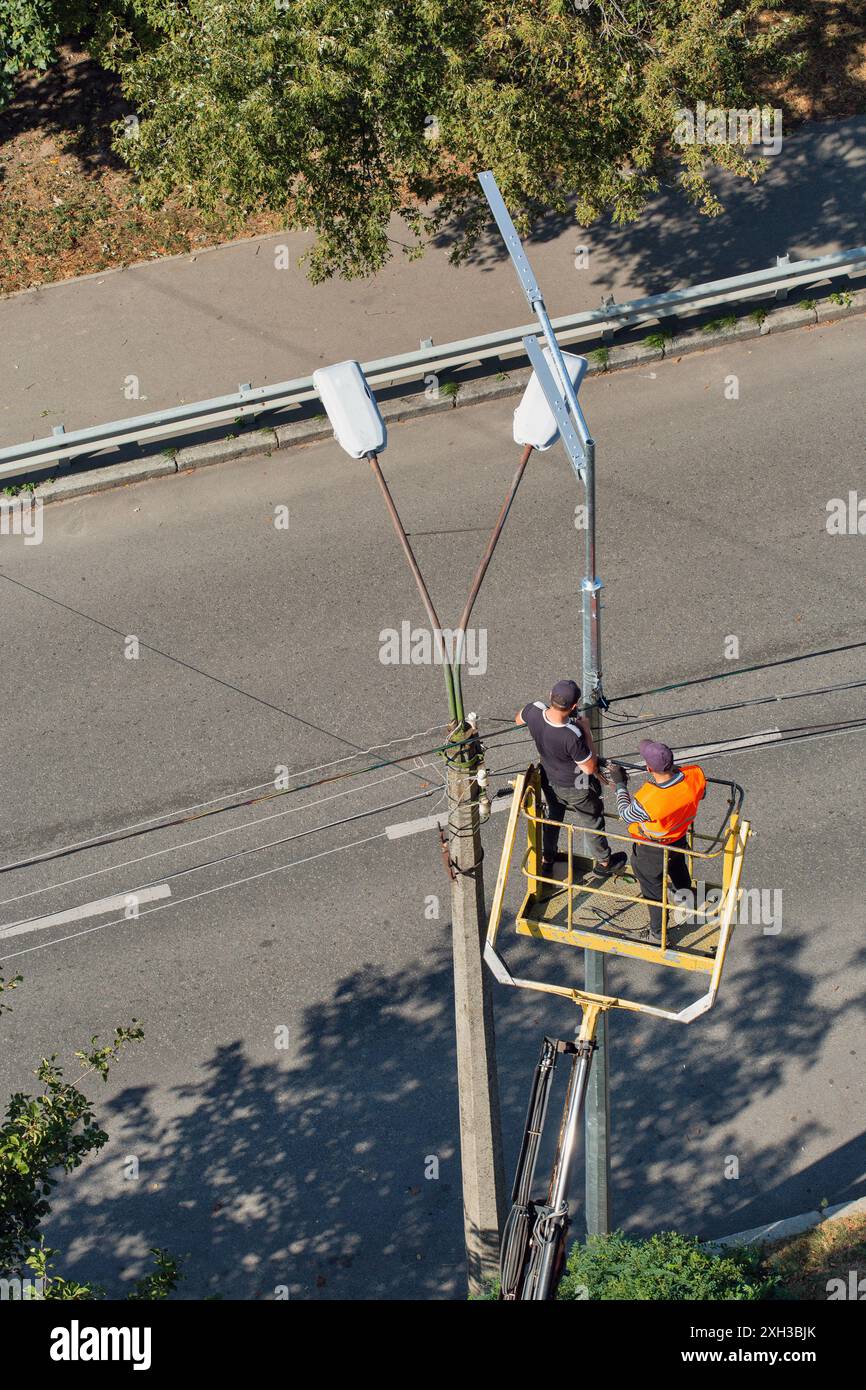Workers installers on a pneumatic car lift are installing a new street ...