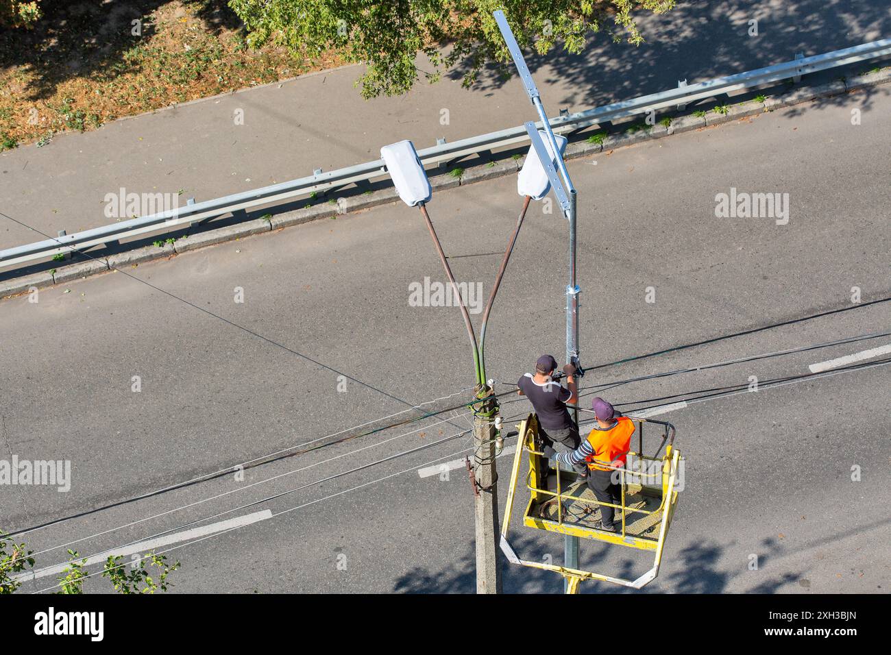Workers installers on a pneumatic car lift are installing a new street ...