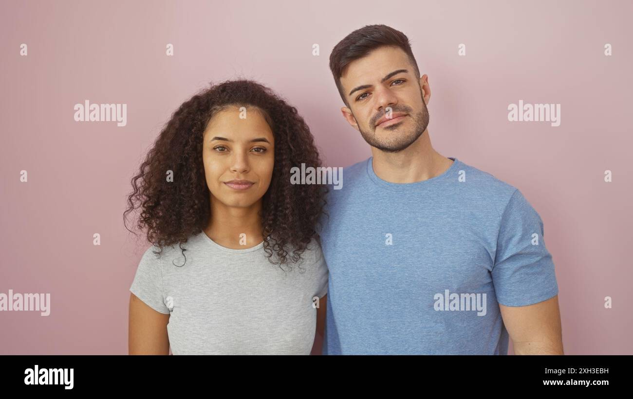 A multicultural couple stands together against a pink background ...