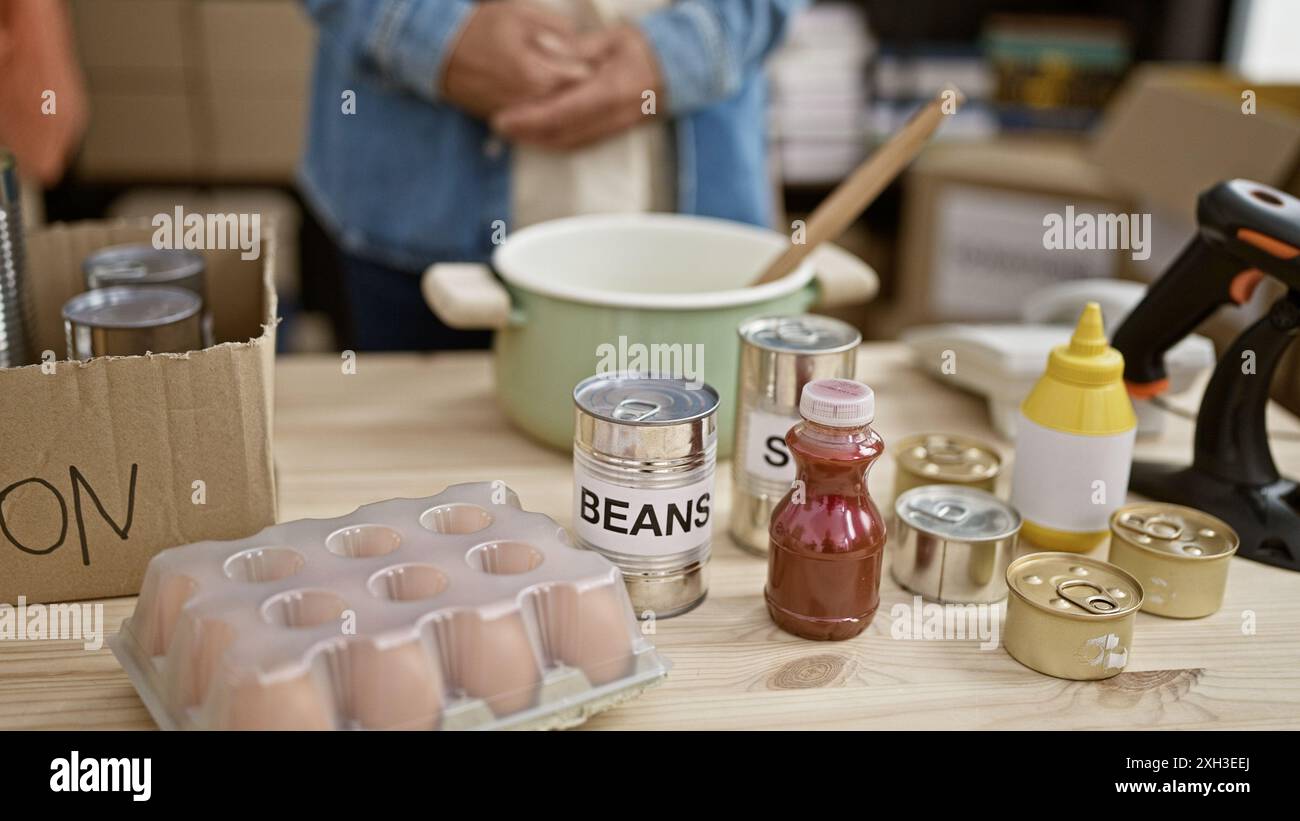 Middle-aged man preparing emergency supplies with canned food, desk ...