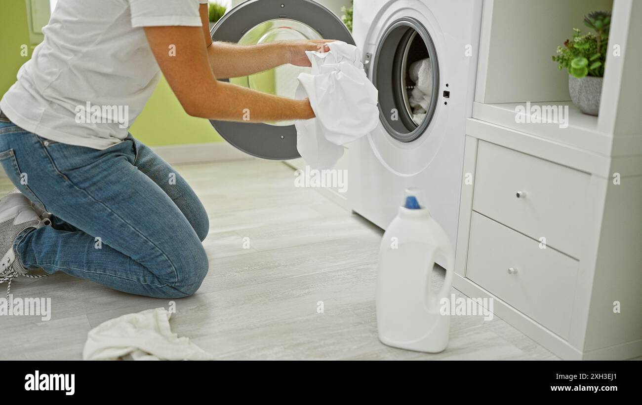 A person in a white shirt and jeans kneels doing laundry in a bright ...