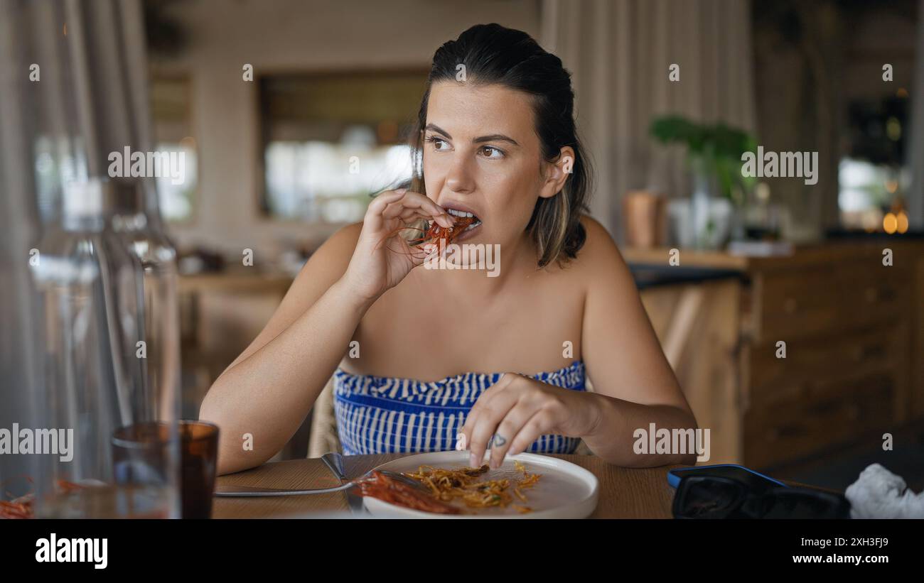 Young hispanic woman eating prawns heads at the restaurant Stock Photo ...