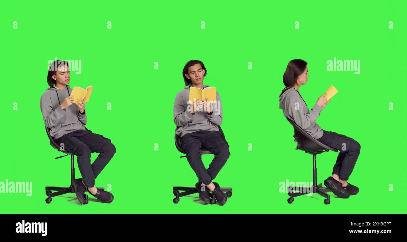 Asian guy reading literature book over greenscreen backdrop, enjoying ...