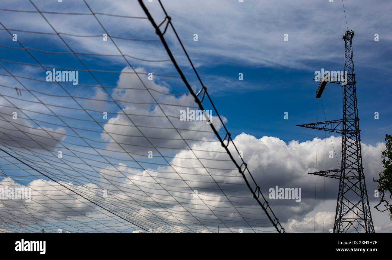 Worker in high visibility clothing atop a electricity pylon tower ...