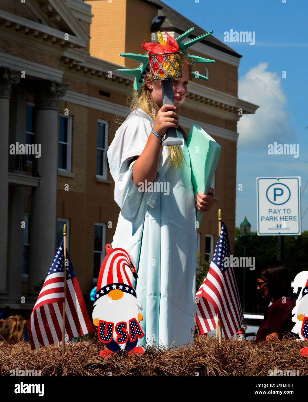 A girl dressed as the American Statue of Liberty rides on a float in a ...