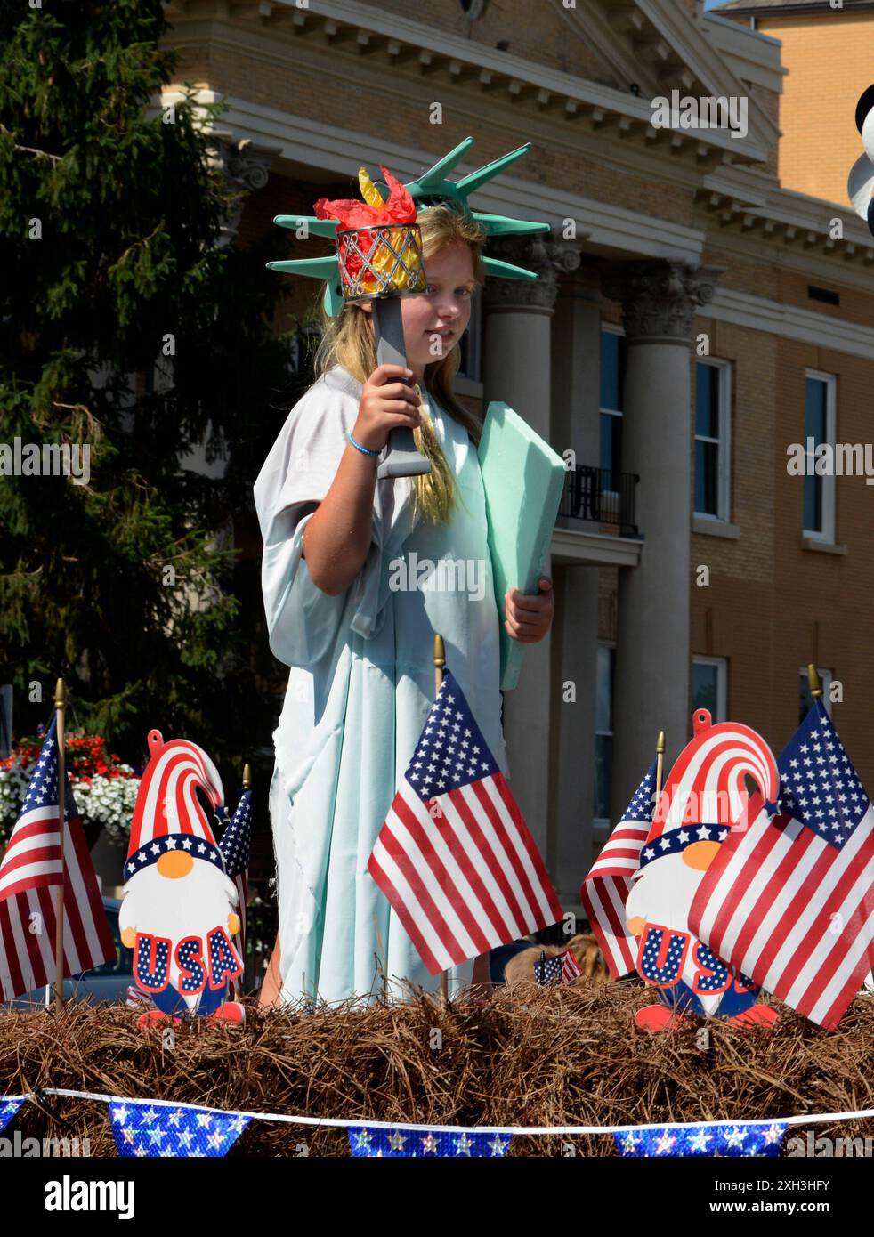 A girl dressed as the American Statue of Liberty rides on a float in a ...