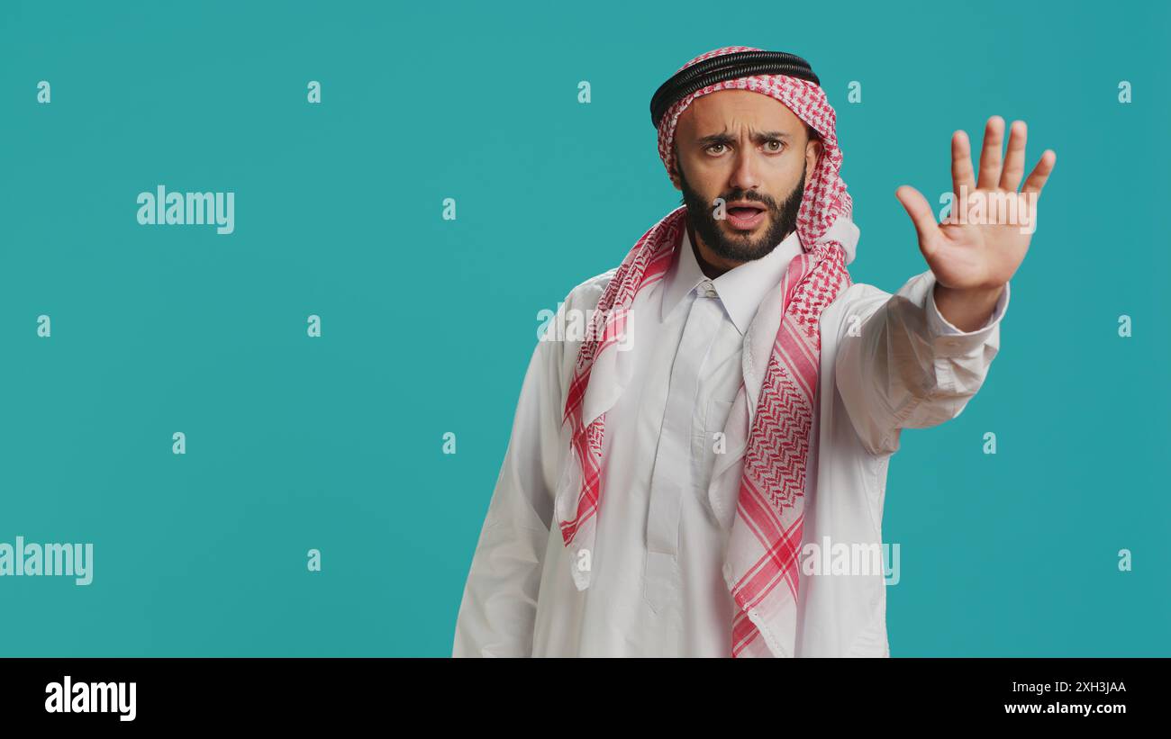 Middle eastern guy doing stop gesture with palm, expressing negativity ...