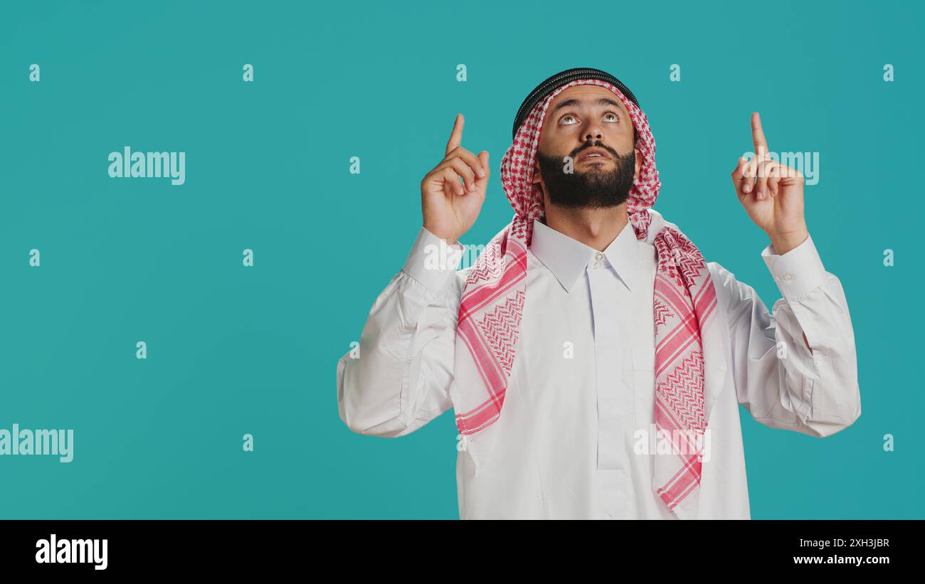 Middle eastern guy looking up above head, pointing and indicating ...