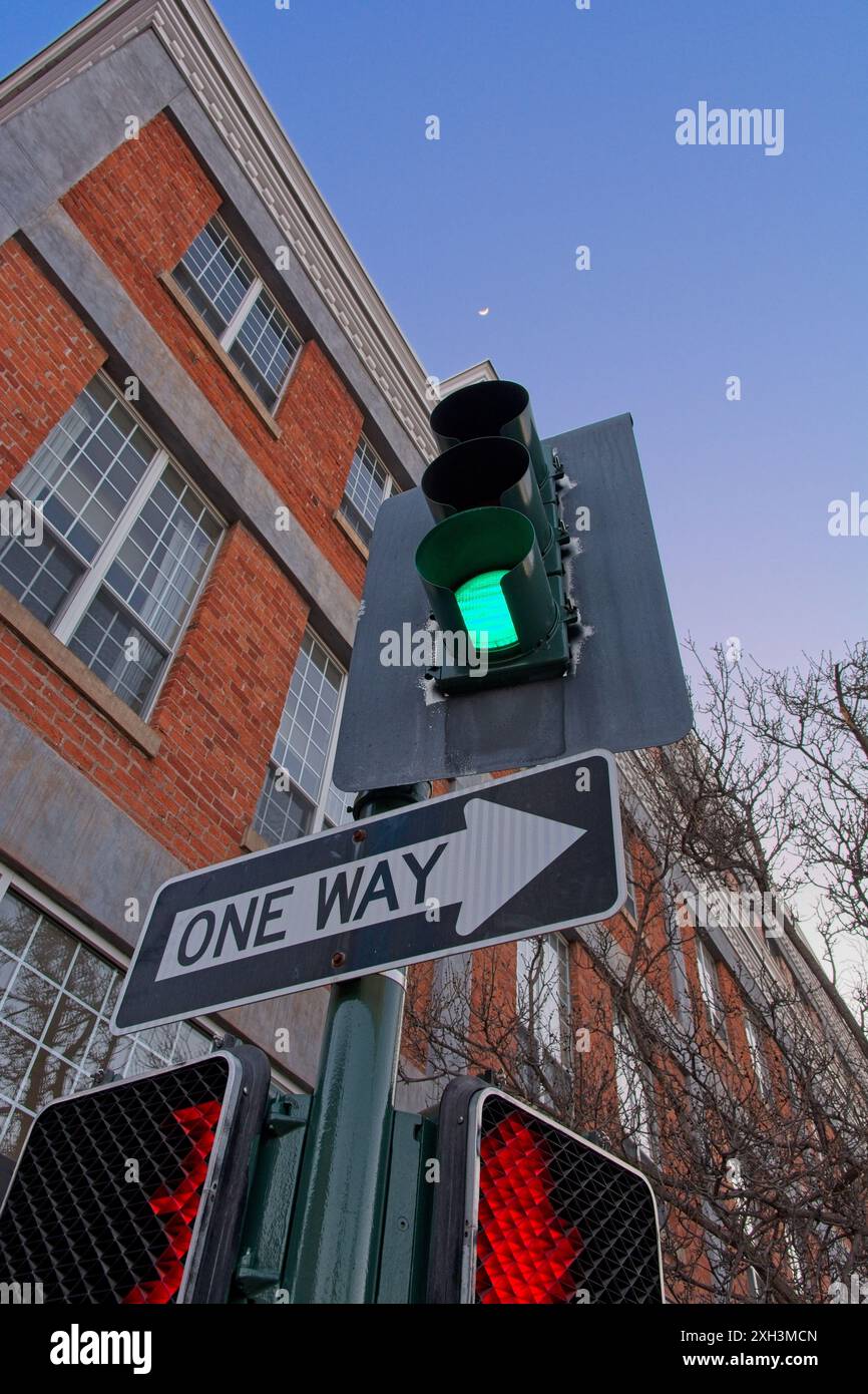 One way sign affixed between green traffic signal, pedestrian crosswalk ...