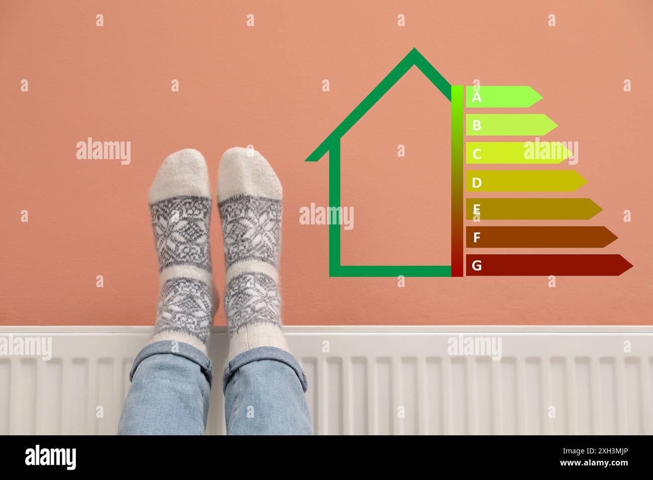 Energy efficiency rating label on color wall and woman warming legs on ...