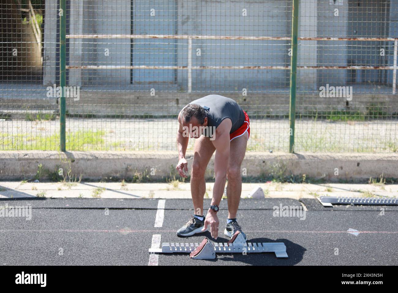 Runner Setting The Starting Blocks On The Track Stock Photo - Alamy
