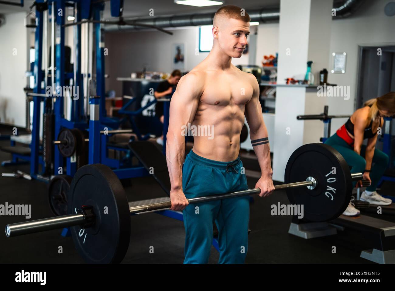 A muscular bodybuilder with perfect athletic shape lifting a barbell ...