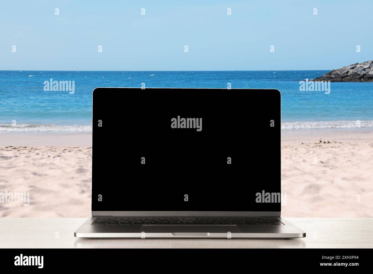 Workplace at beach, distant office. Table with laptop on sandy seashore ...