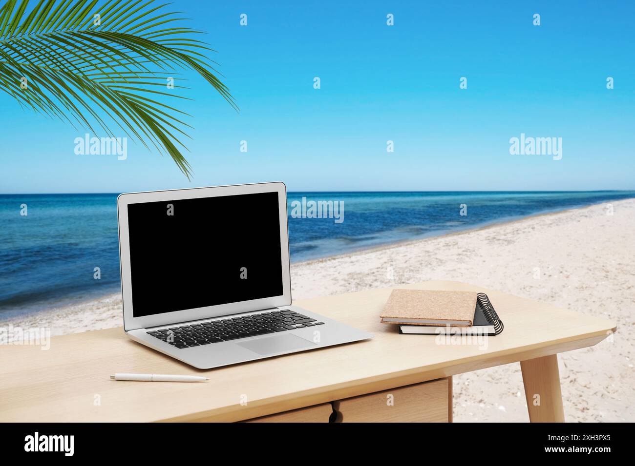 Workplace at beach, distant office. Table with laptop on sandy seashore ...