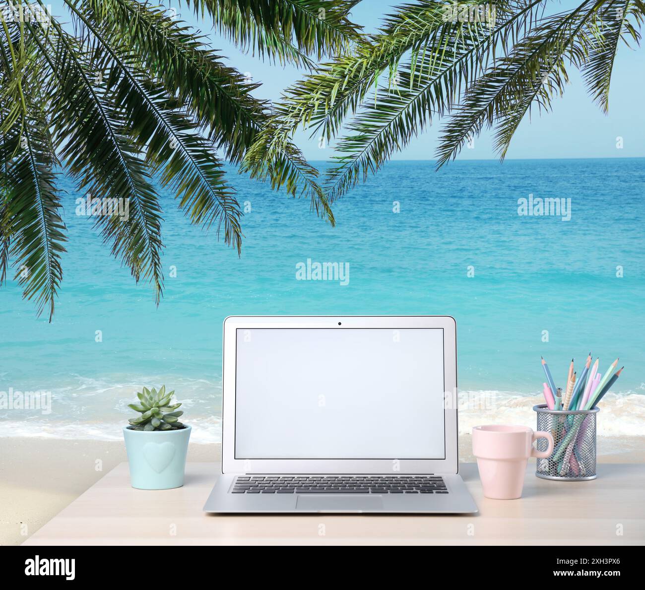 Workplace at beach, distant office. Table with laptop on sandy seashore ...
