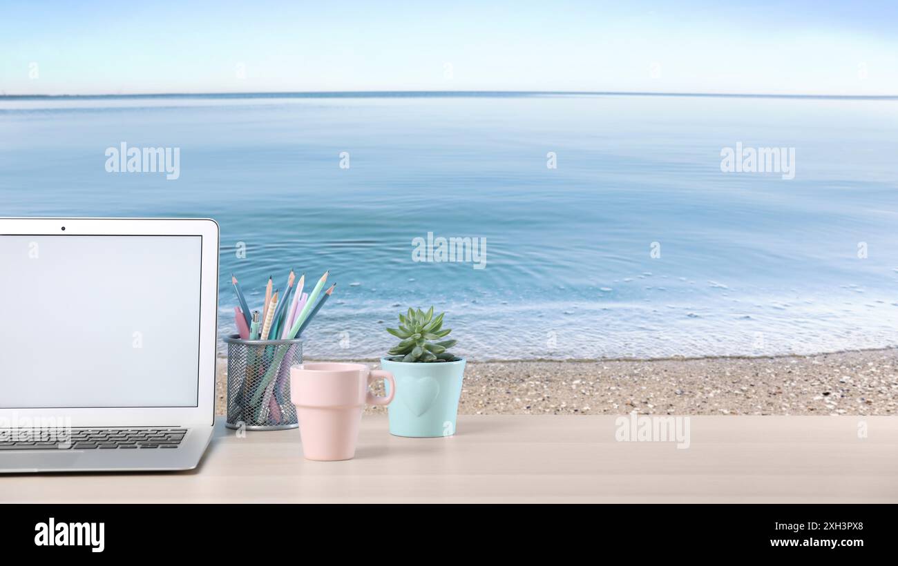 Workplace at beach, distant office. Table with laptop on sandy seashore ...