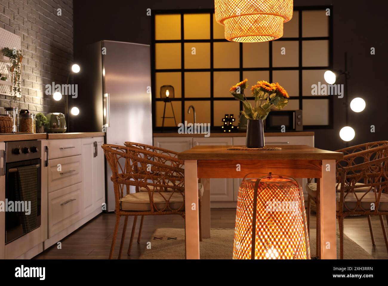 Stylish interior of modern kitchen with glowing lamps, dining table ...