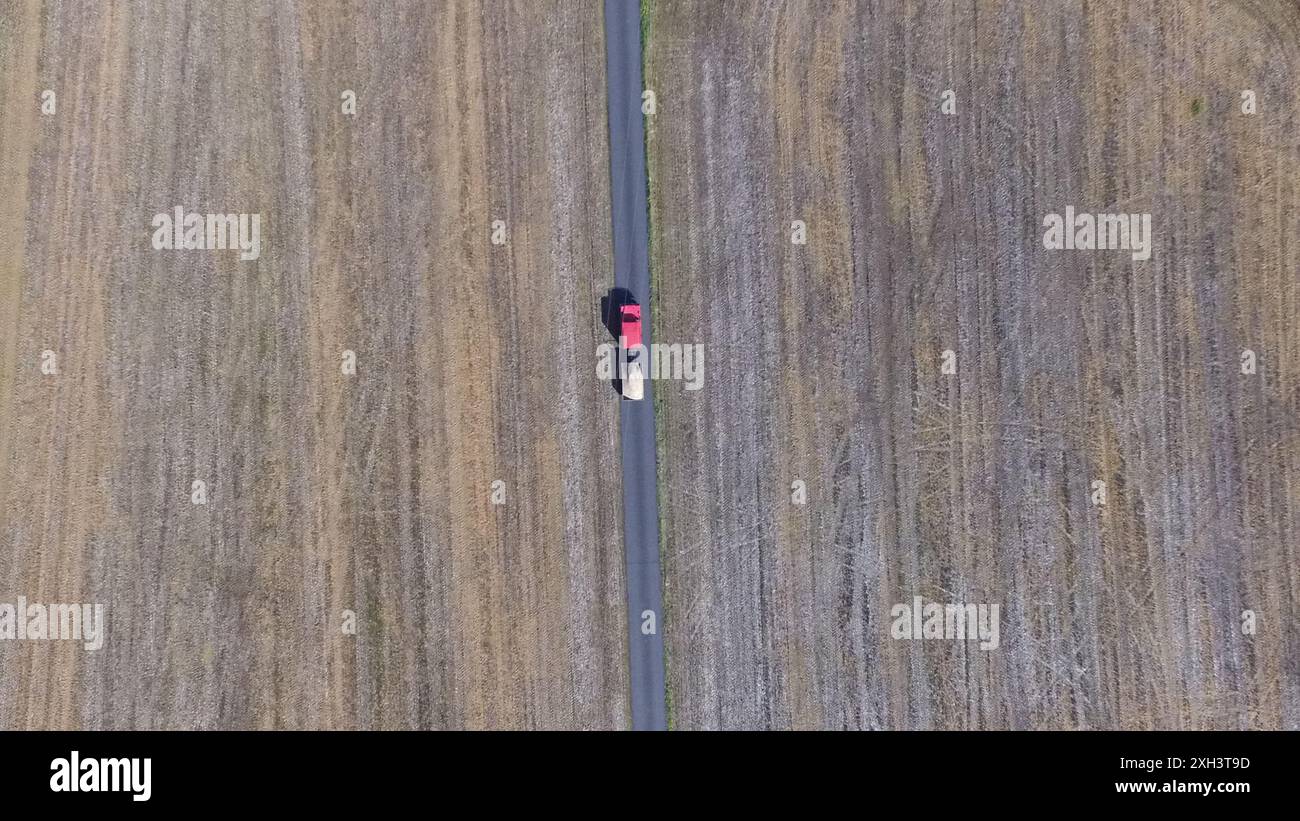 Field with car driving on road through middle Stock Photo - Alamy