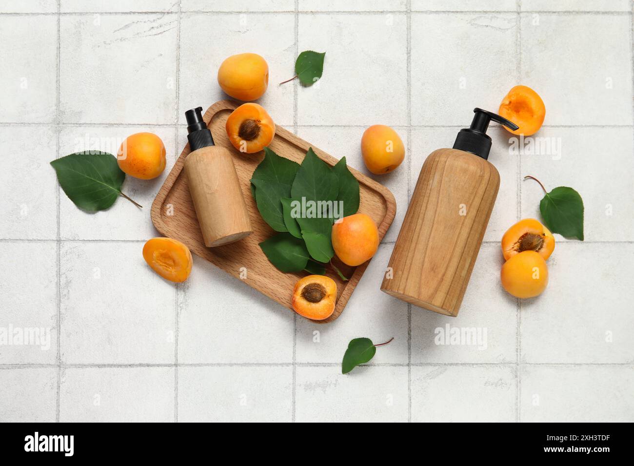 Bottles of cosmetic products with fresh apricots on white tile ...