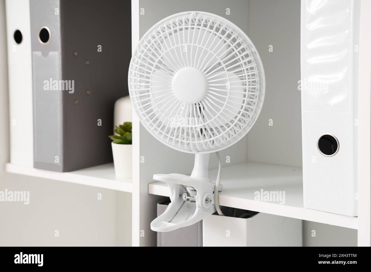 Electric fan on shelving unit in office Stock Photo - Alamy