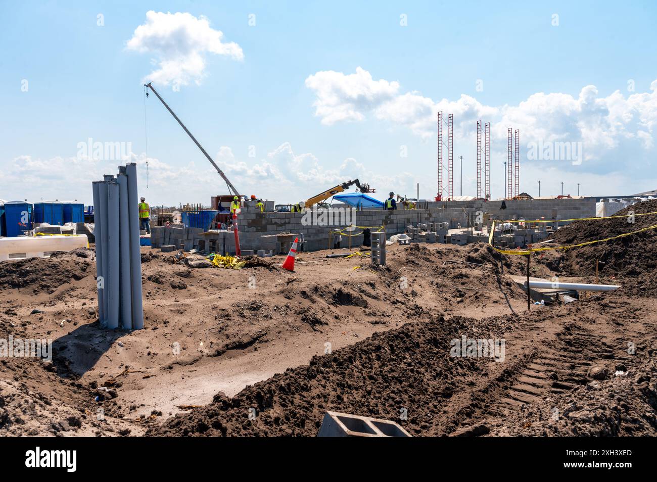 Construction crews build the exterior walls of the future hangar three ...