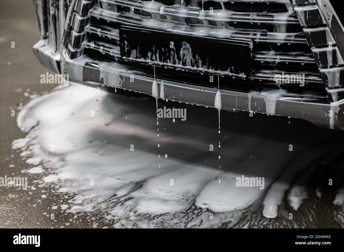 Foam drips from the bumper of a black car. Car wash Stock Photo - Alamy