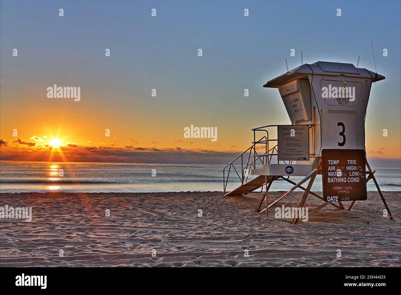 The sunrises over the atlantic ocean lighting a lifeguard stand in ...