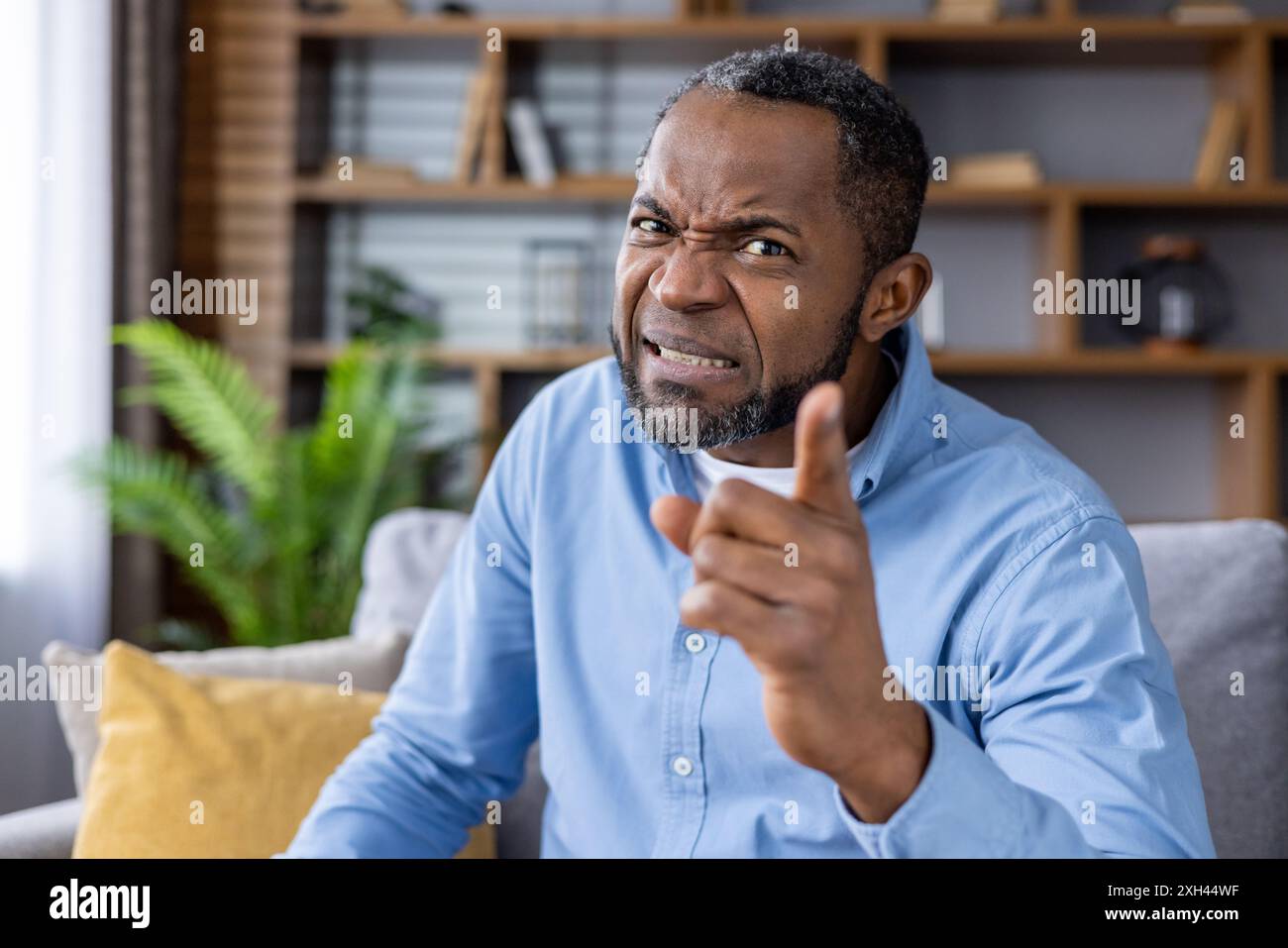 Angry man in blue shirt pointing finger at camera with intense facial ...