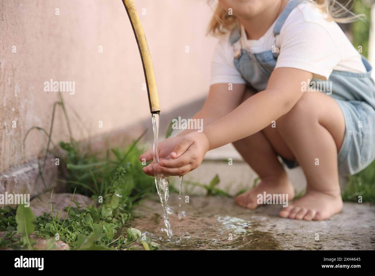 Water scarcity. Little girl drinking water from tap outdoors, closeup ...