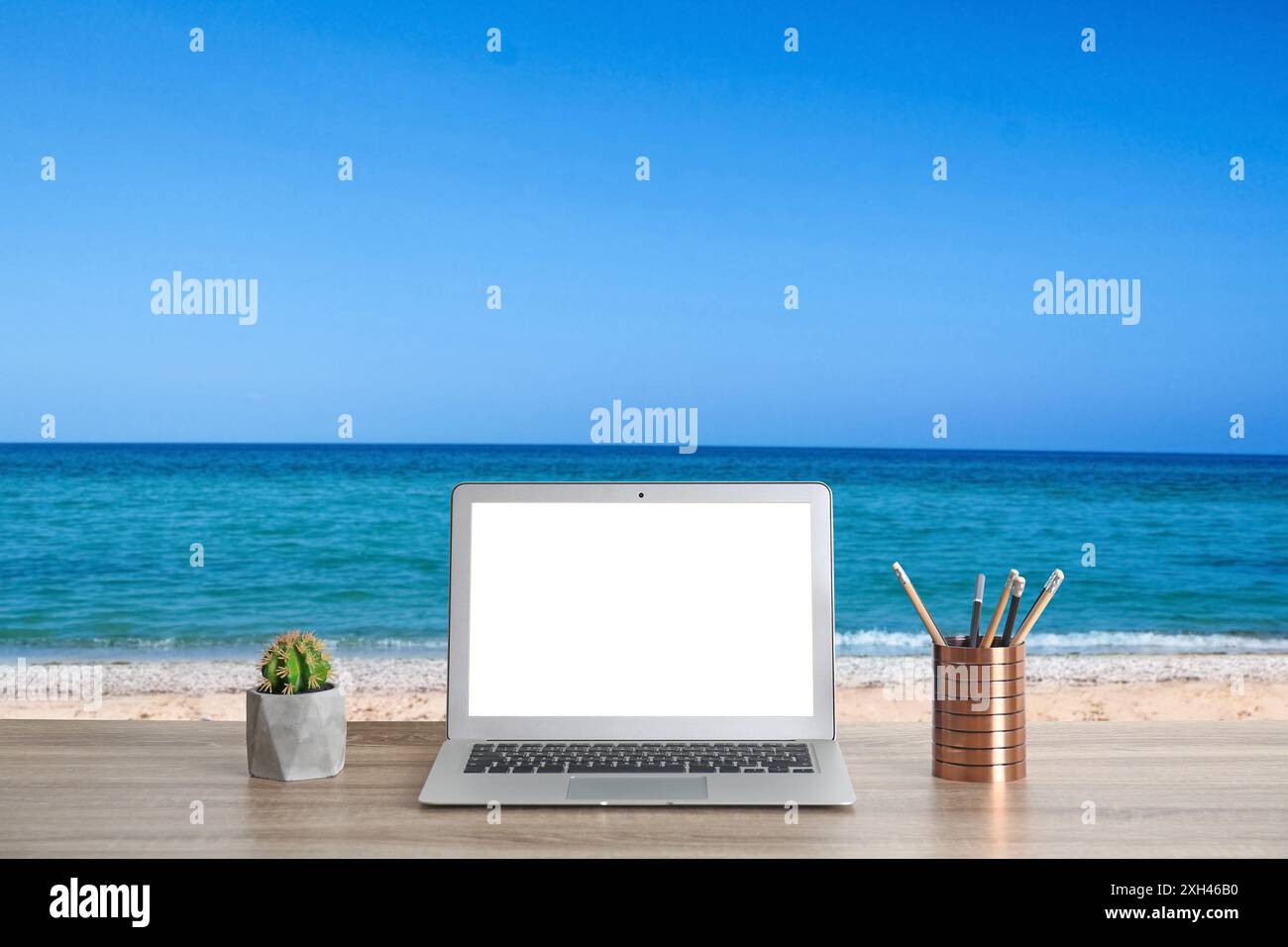 Workplace at beach, distant office. Table with laptop on sandy seashore ...