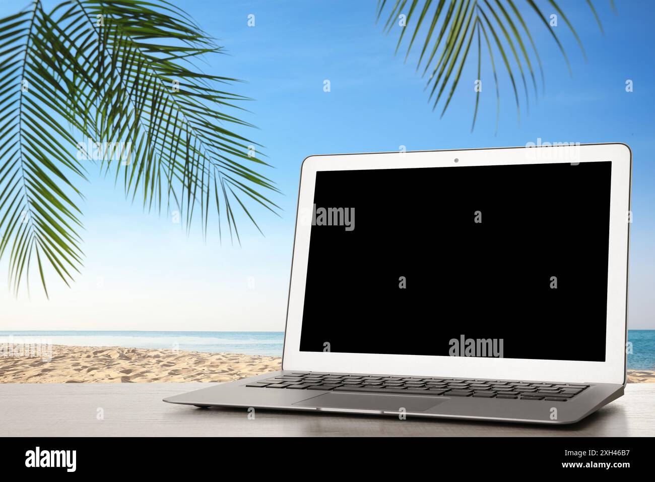Workplace at beach, distant office. Table with laptop on sandy seashore ...