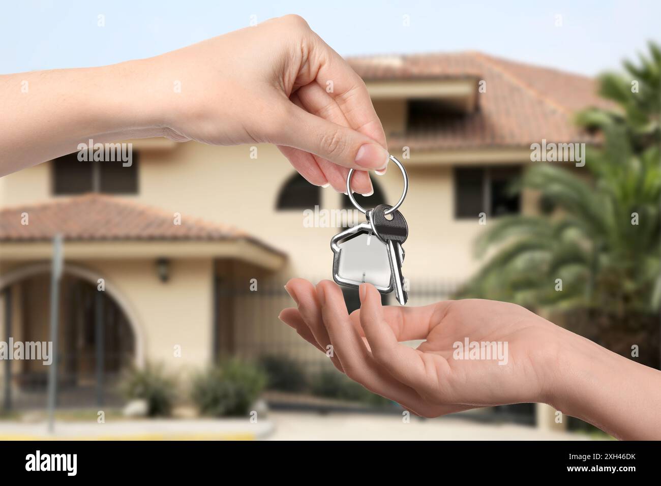 Real estate agent giving house key to new owner against beautiful ...
