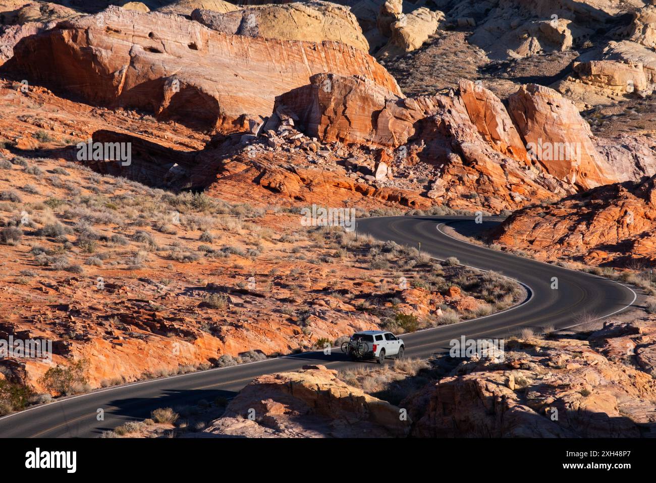 A lone SUV car driving along a curving desert highway landscape at ...