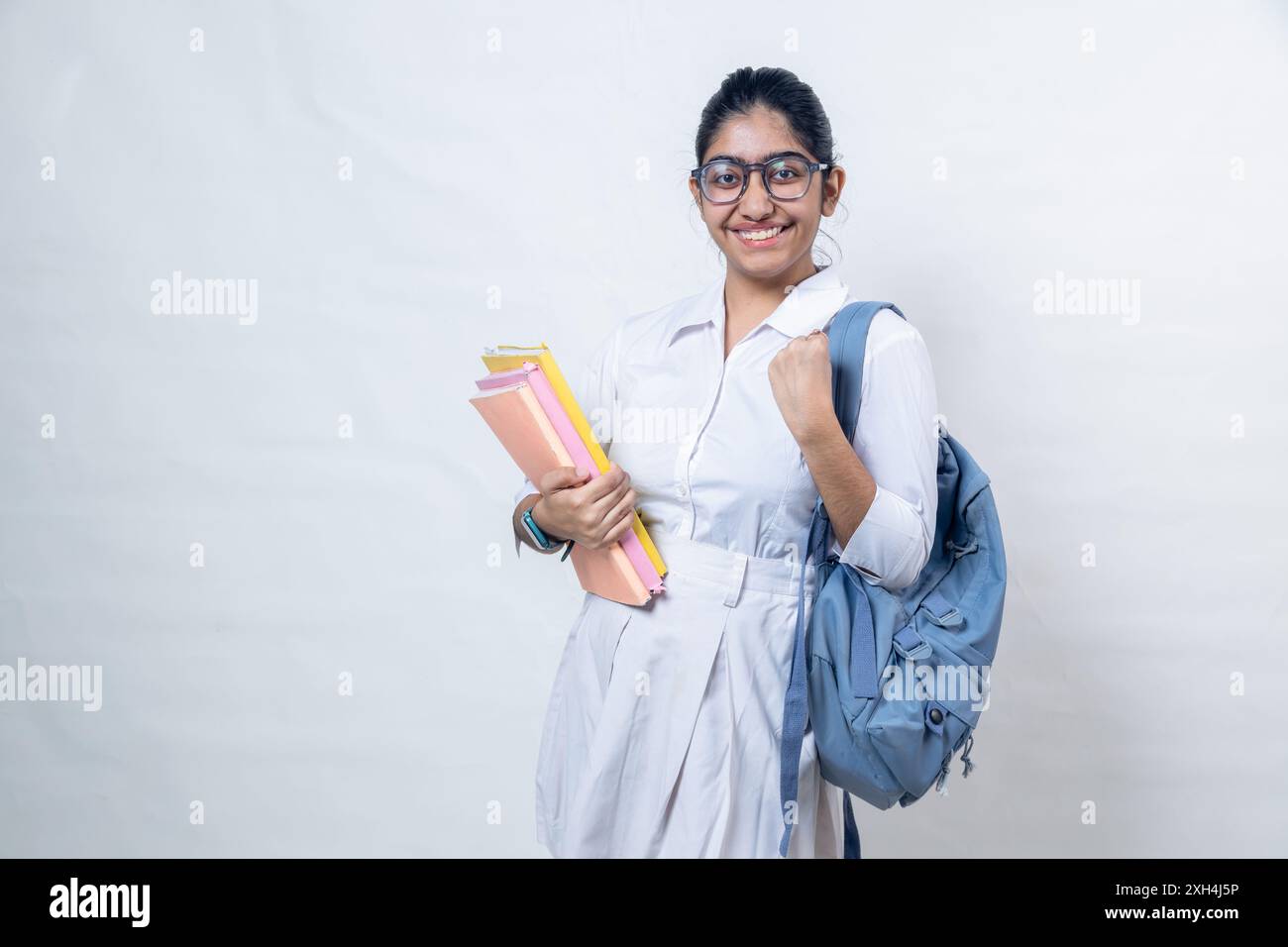 Happy indian school girl student standing with notebook and bag in hand ...