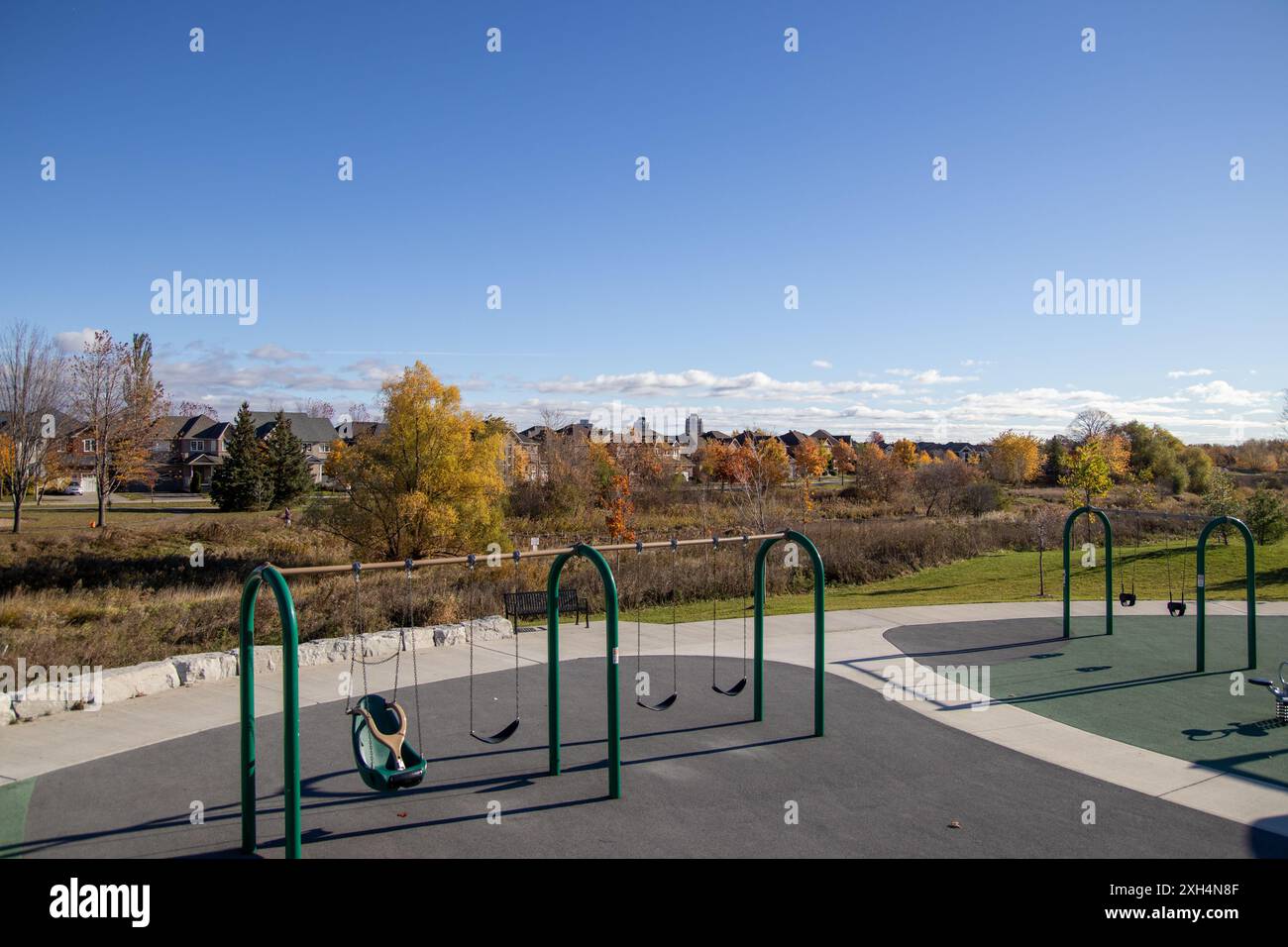 Sunny playground scene - empty swings - vibrant autumn foliage - clear ...