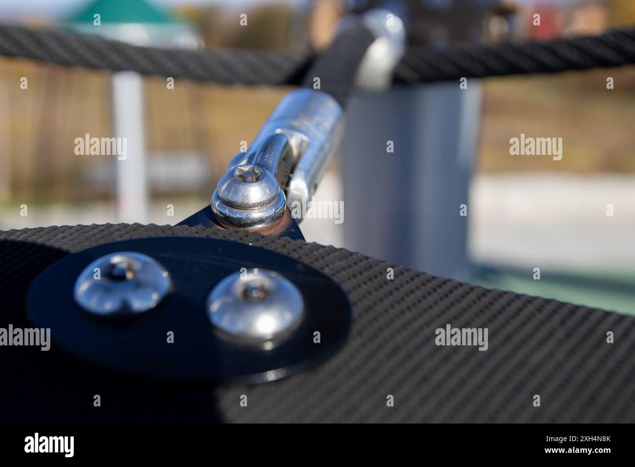 Close-up of a metallic carabiner attached to a black, woven safety net ...