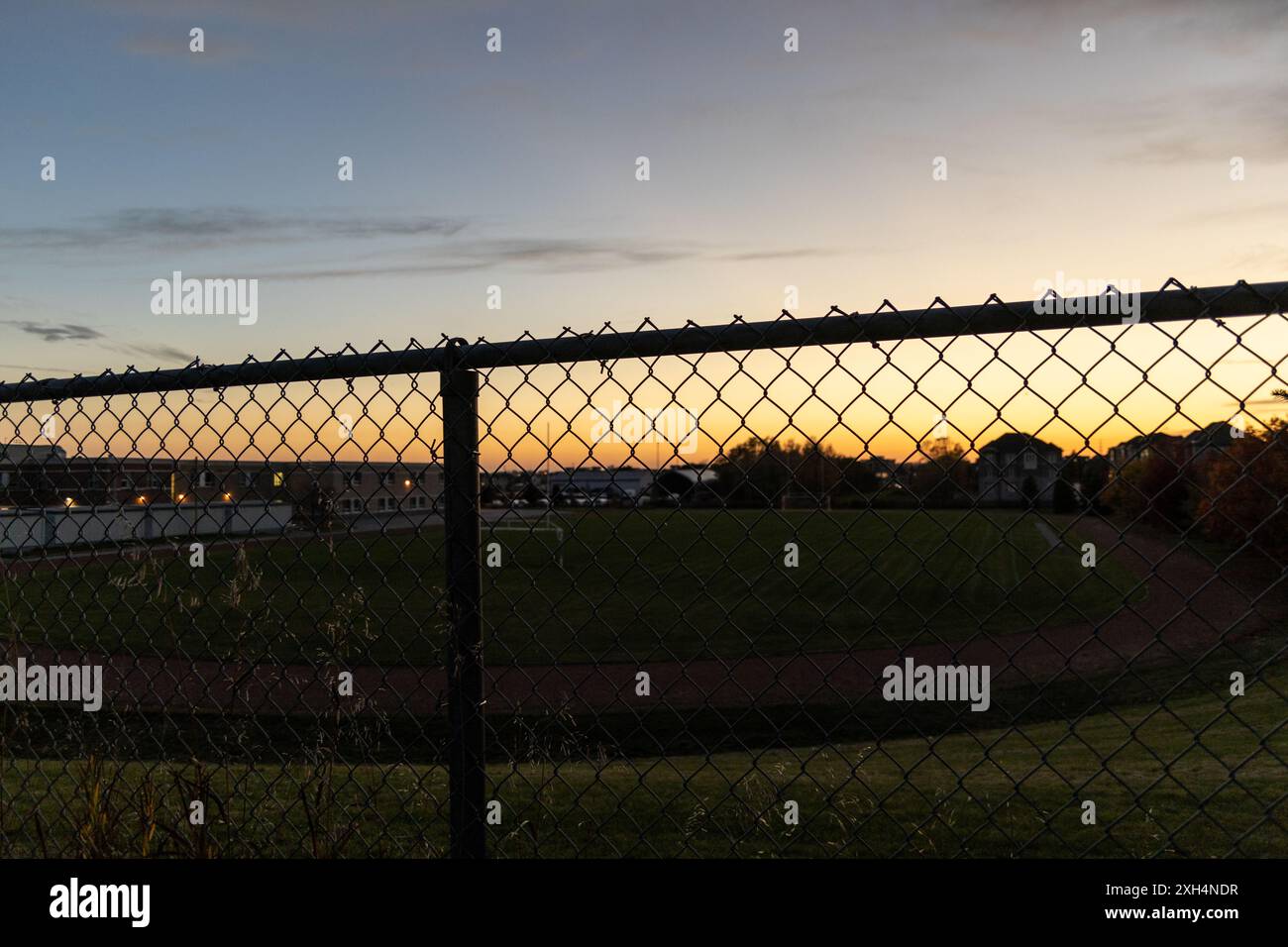 Sunset hues backlighting a chain-link fence - golden hour sky gradient ...