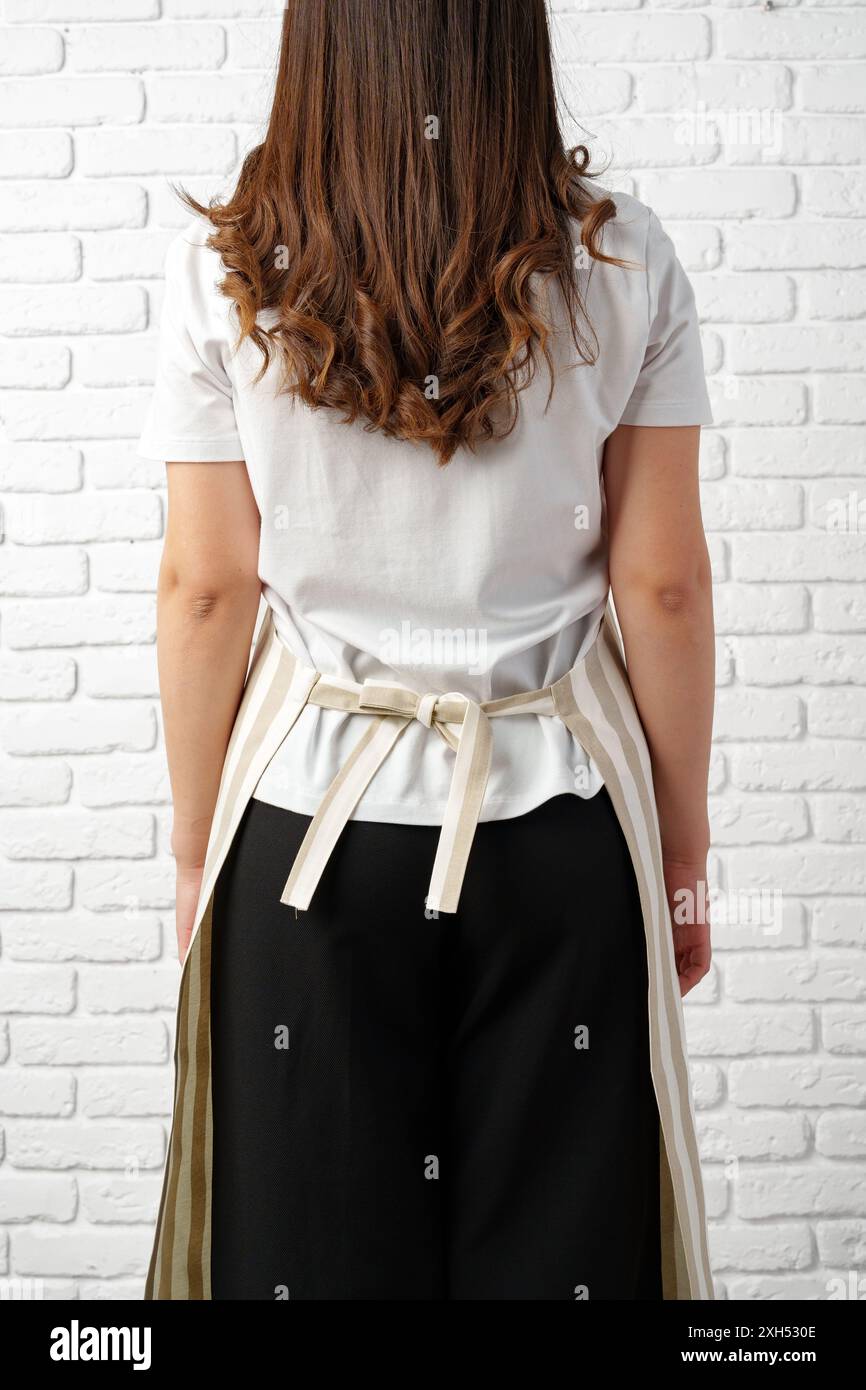 Back view Woman Wearing Apron in Front of a White Brick Wall Stock ...