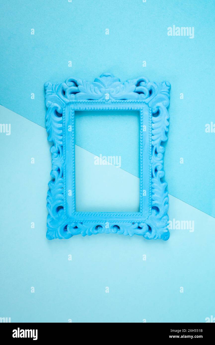 Empty blue painted baroque frame on blue shades color background, pop ...