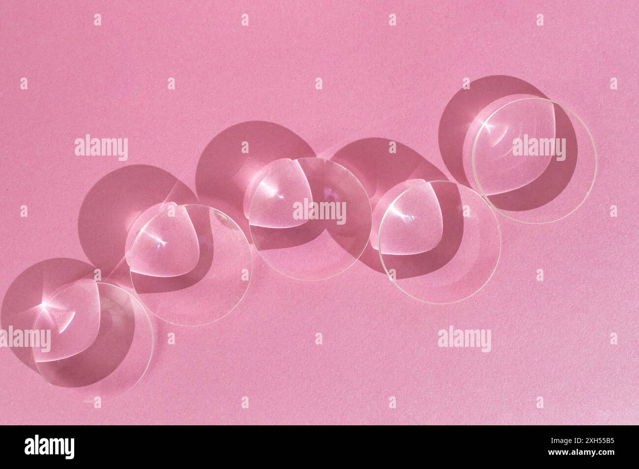 Five magnifying lenses flat lay on pink background with hard shadows ...