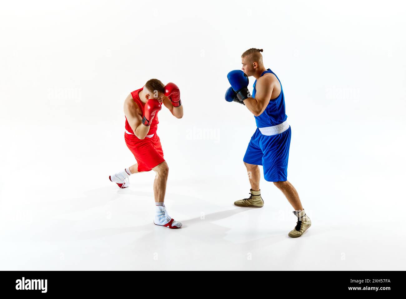 Two young athletes fighting. Boxer in red attire stands defends himself ...