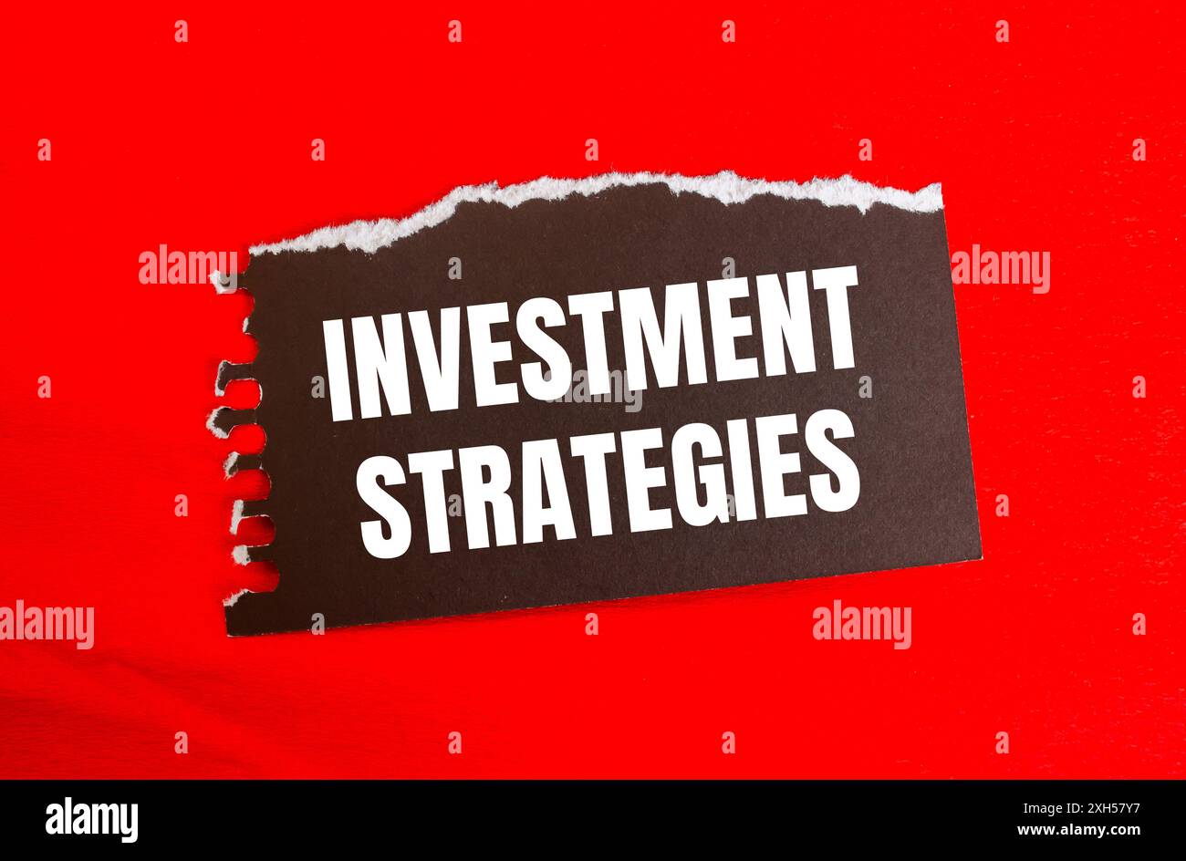 Investment strategies message written on ripped torn black paper piece ...