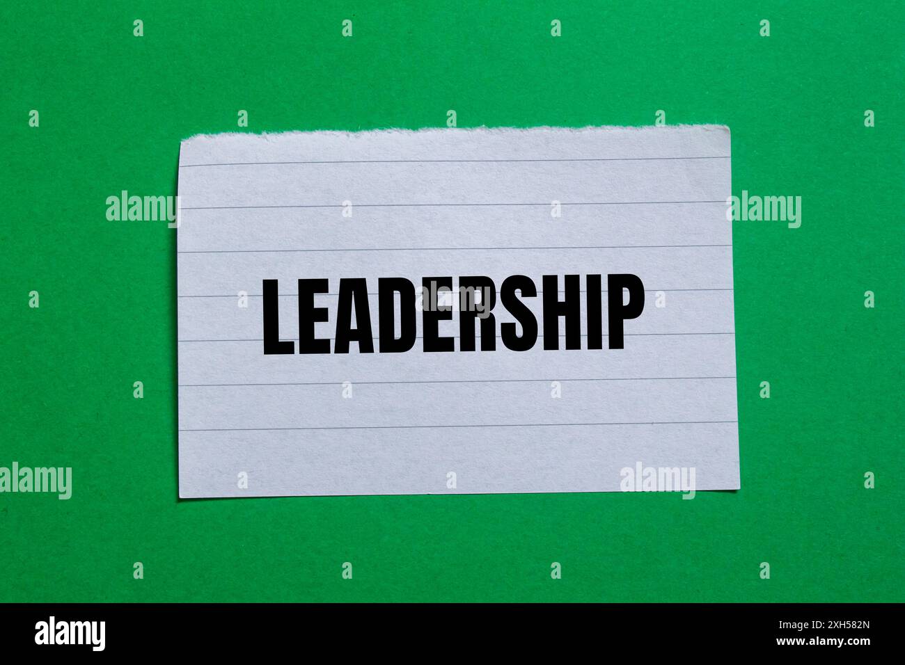 Leadership message written on ripped torn paper piece with green ...