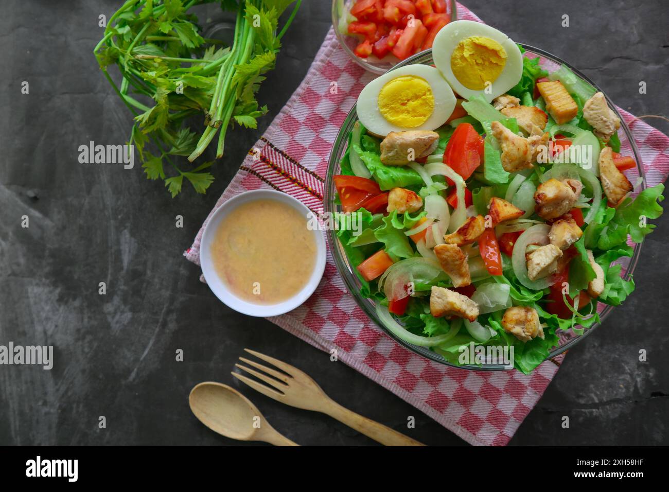 A cesar salad bowl filled with lettuce, tomatoes, egg and chicken. The ...