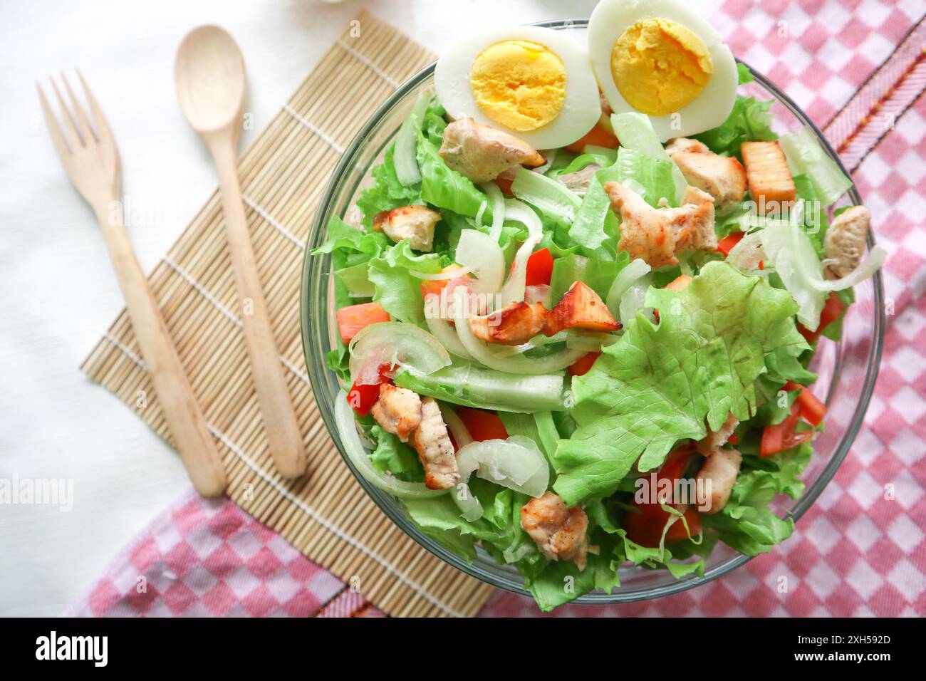 A cesar salad bowl filled with lettuce, tomatoes, egg and chicken. The ...