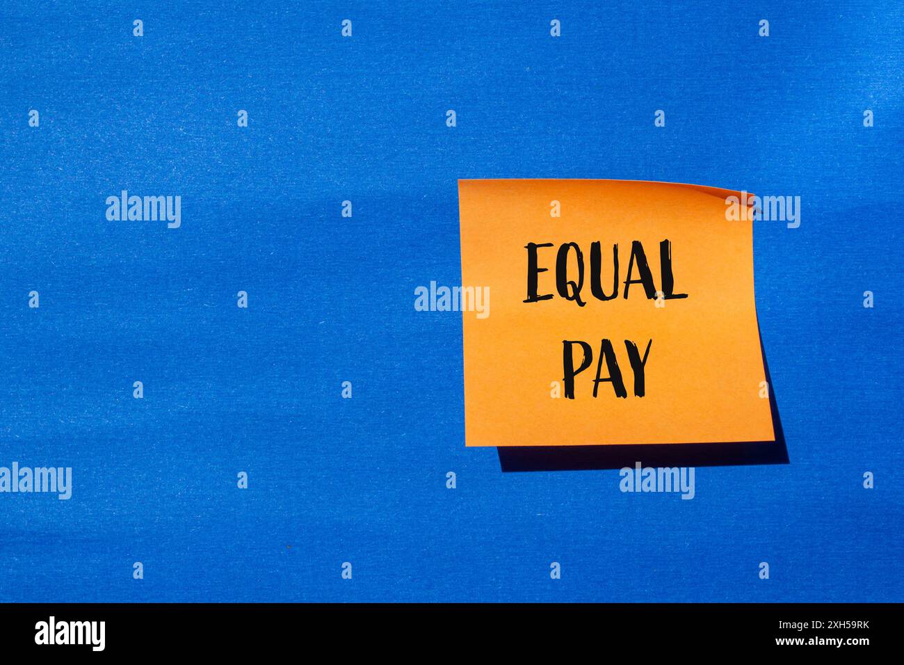 Equal pay message written on orange paper with blue background ...